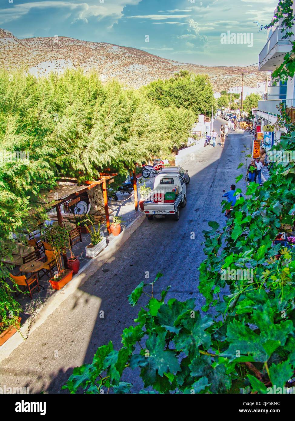 A vertical shot of cars driving on the road of the beautiful village of ...