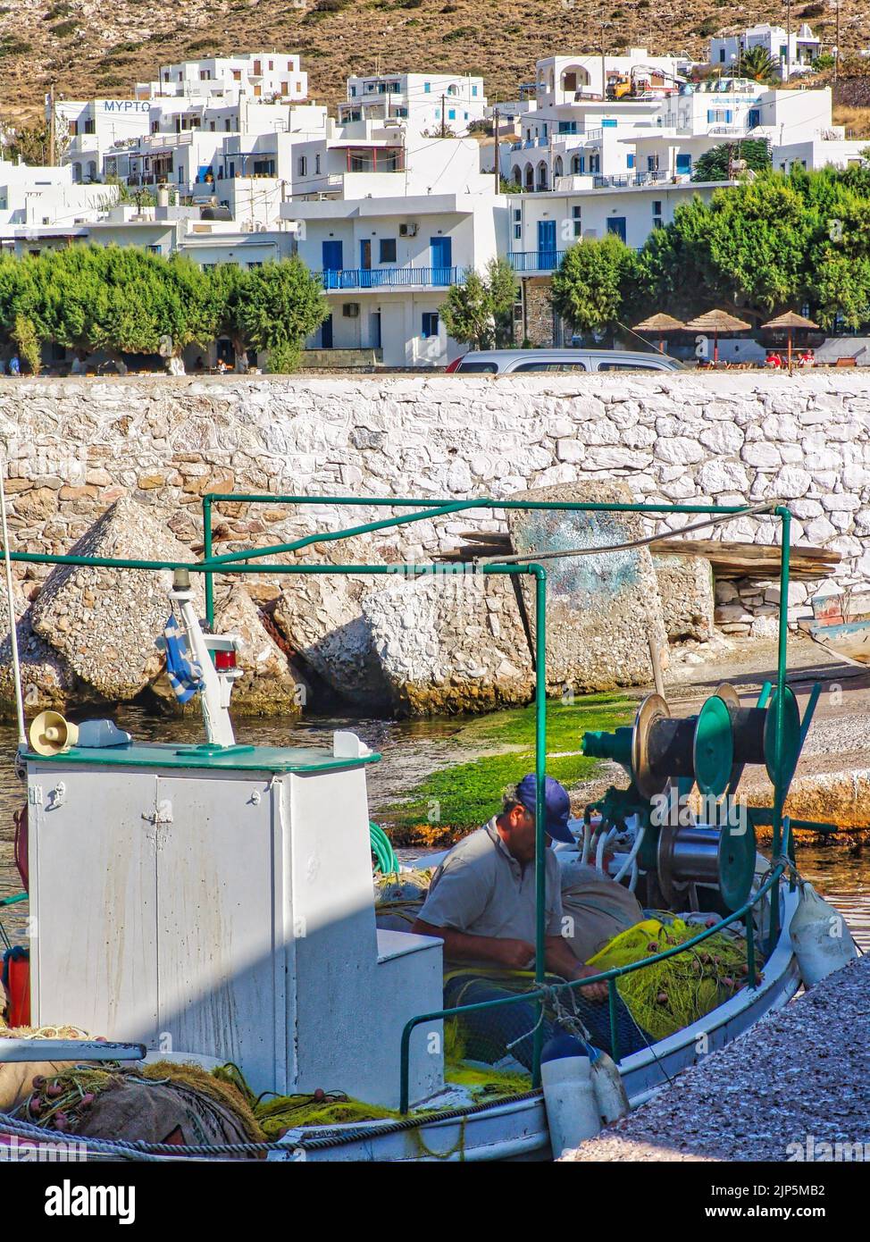 A vertical shot of a boat in the water docked on a port near Kamares ...