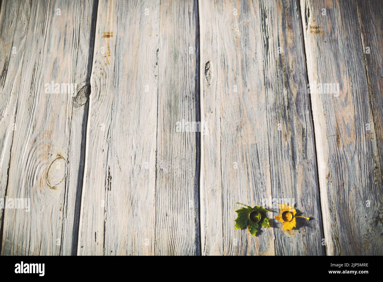 Two wedding rings on leaves on a wooden background Stock Photo - Alamy