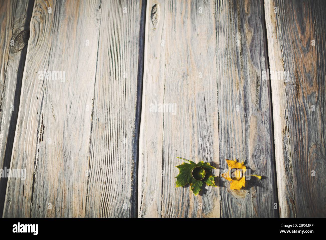 Two wedding rings on leaves on a wooden background Stock Photo - Alamy