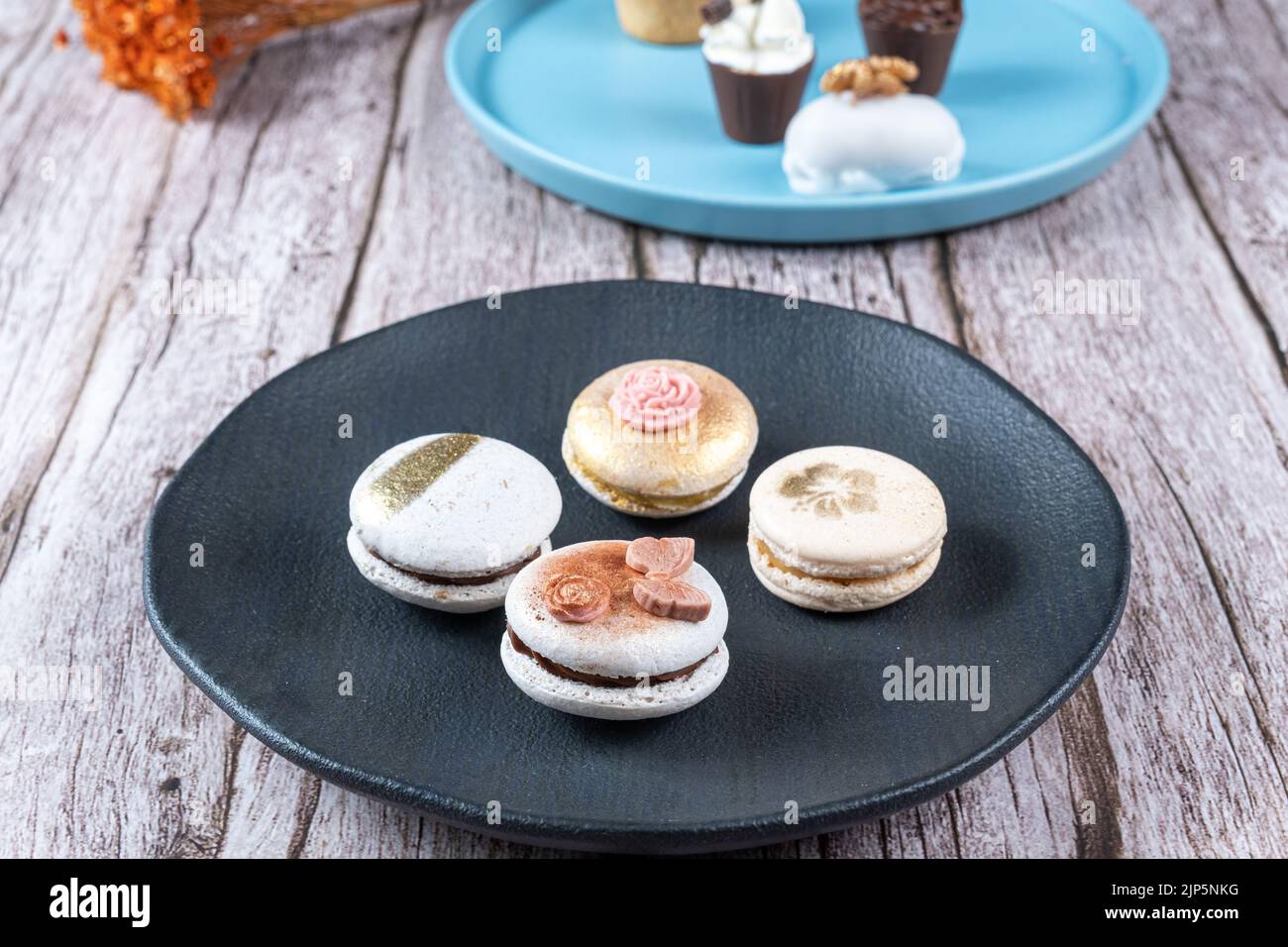 Four macarons, decorated with edible ink and fondant, on a black plate ...