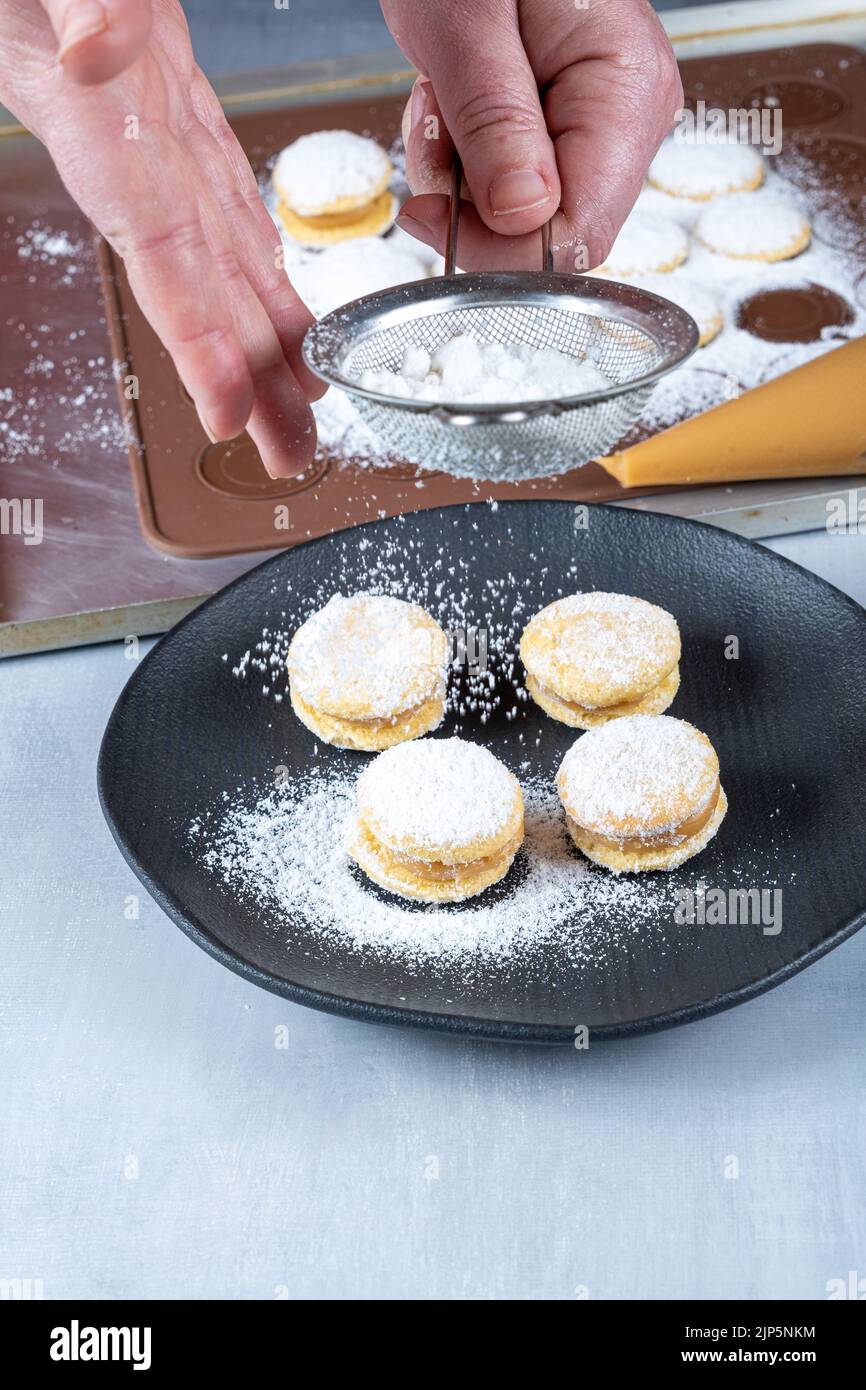 Confectioner sprinkling sugar on four wedding sweet treats. Brazilian ...