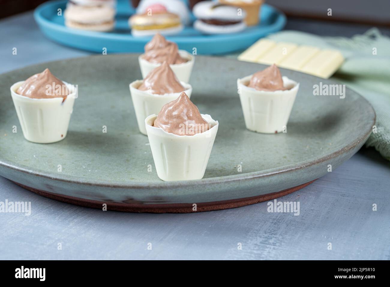 Closeup of small white chocolate cups filled with milk chocolate mousse ...