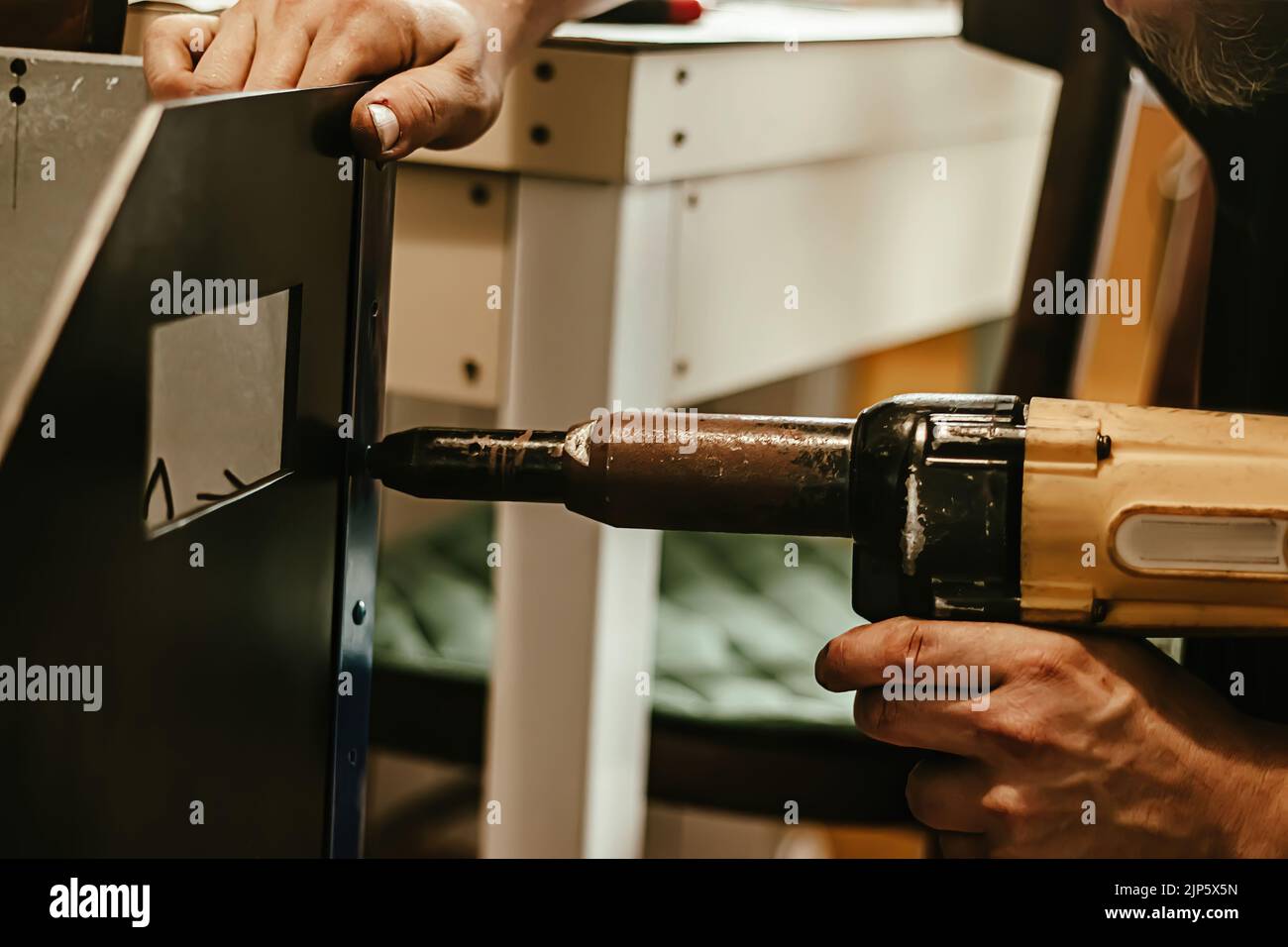 Male worker uses electric riveting gun. Hand holding riveting machine ...