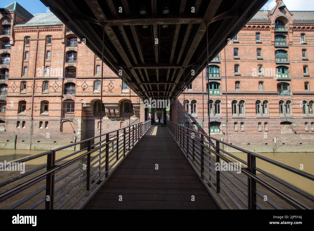 A narow bridge over a canal between red brick buildings in ...