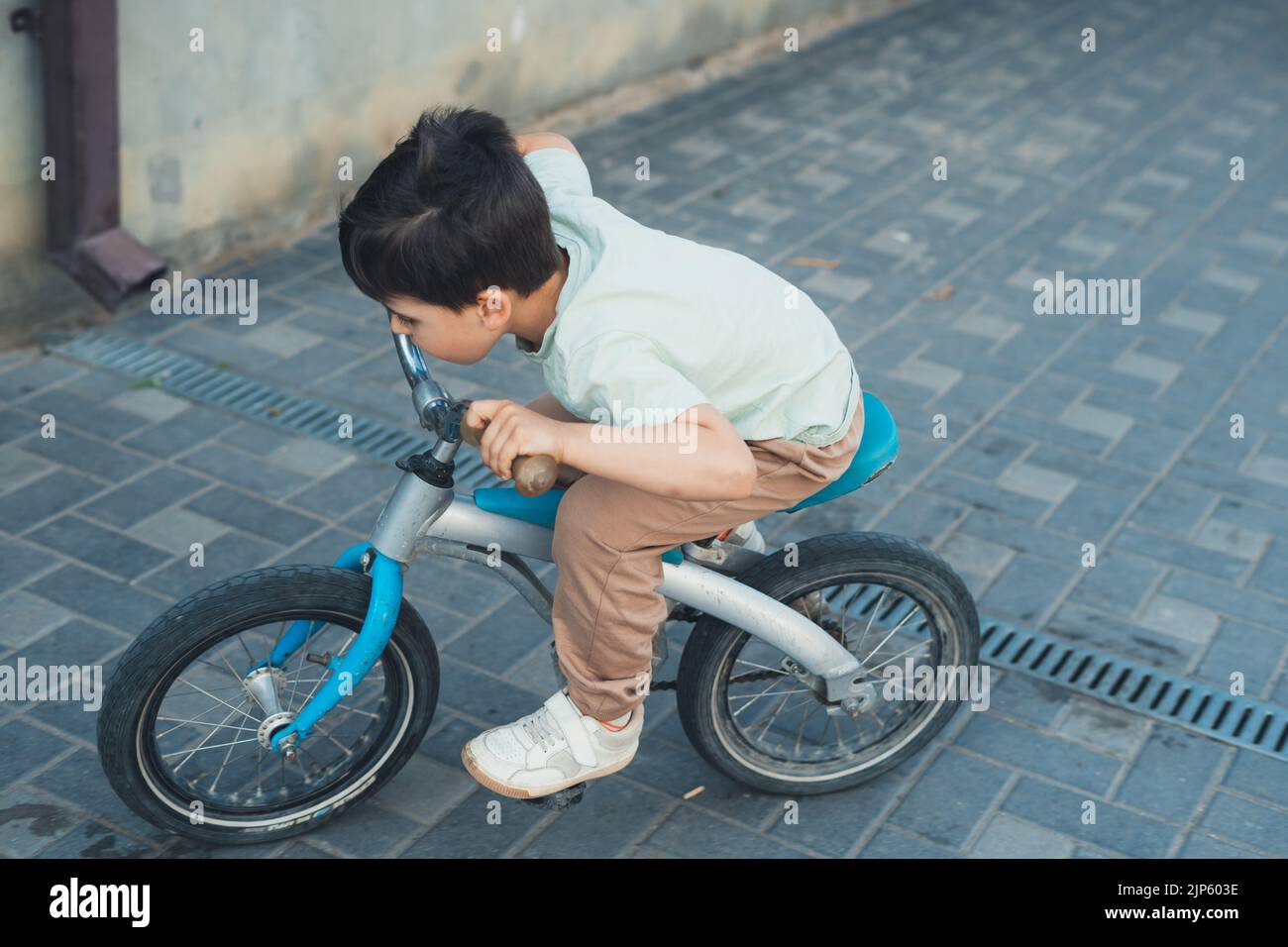 Child playing racing on bike in the home yard. Preschooler outdoor ...