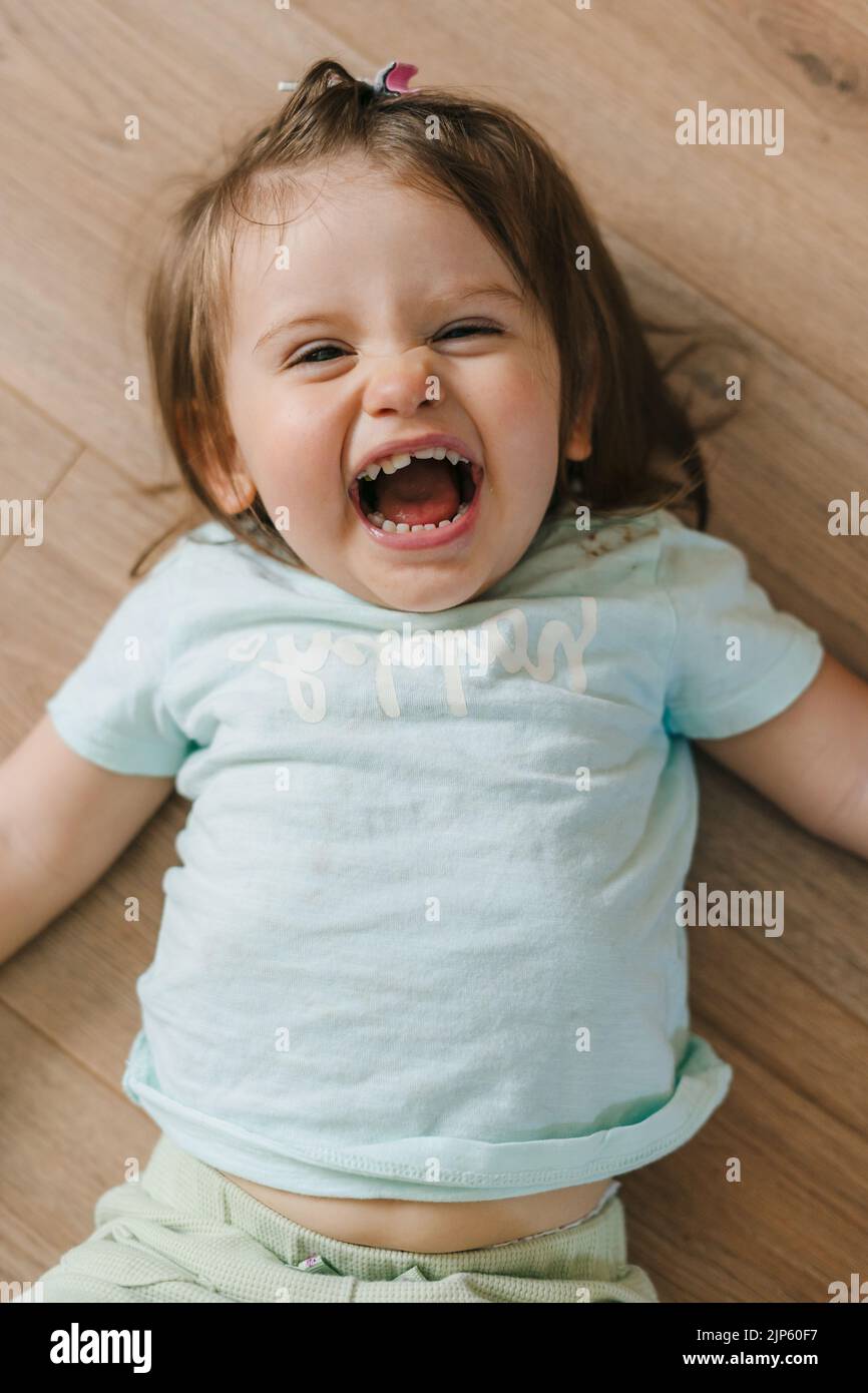Smiling baby girl lying on her back looking up at camera and smiling. Baby development Stock ...
