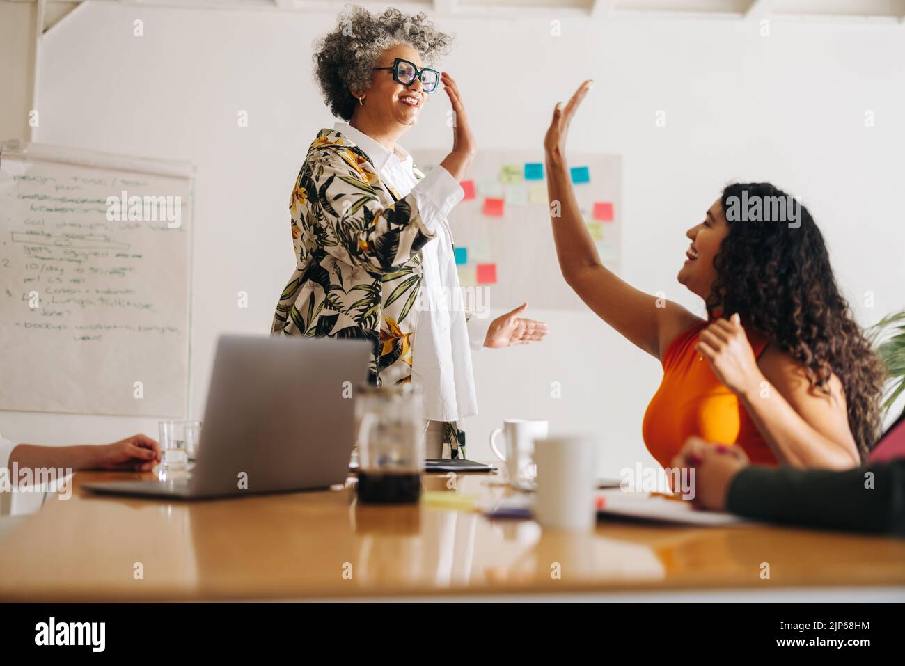 businesswomen high fiving each other during a meeting in a boardroom ...