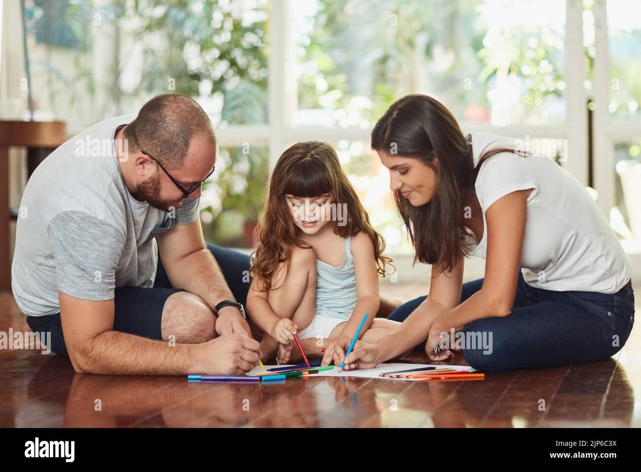 Raising a creative little girl. a mother and father drawing together ...