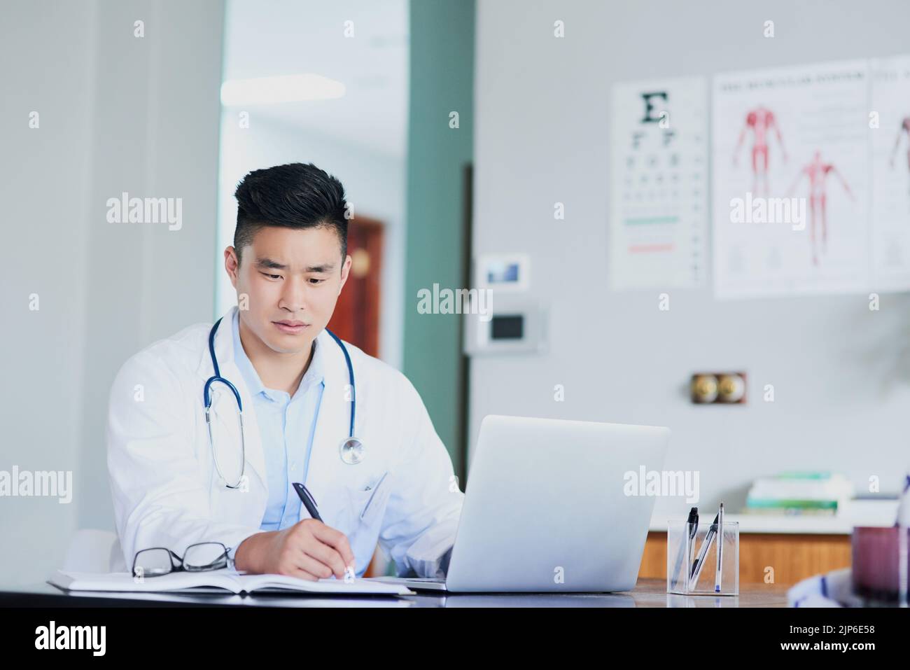 Checking his appointments. a young male doctor making notes while ...