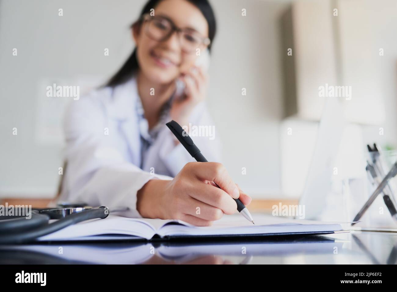 Checking her schedule. a young female doctor making notes while working ...