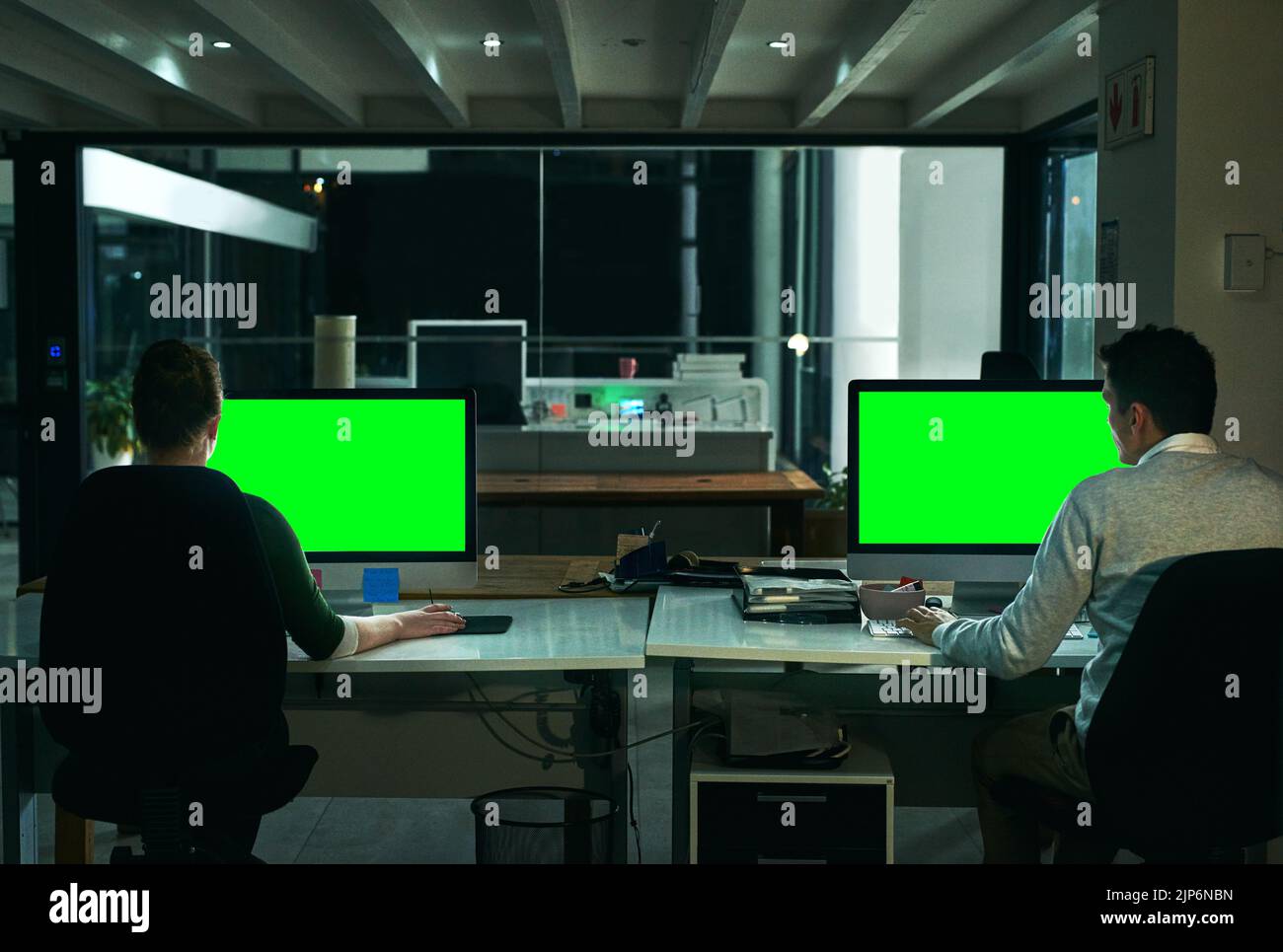 Working the late shift. Rearview shot of two businesspeople working on ...