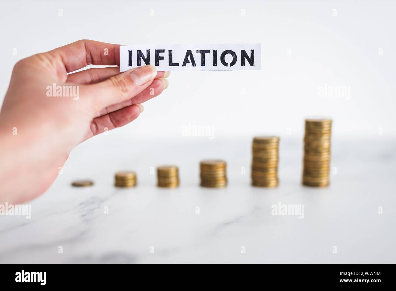 inflation text in front of growing stacks of coins representing ...