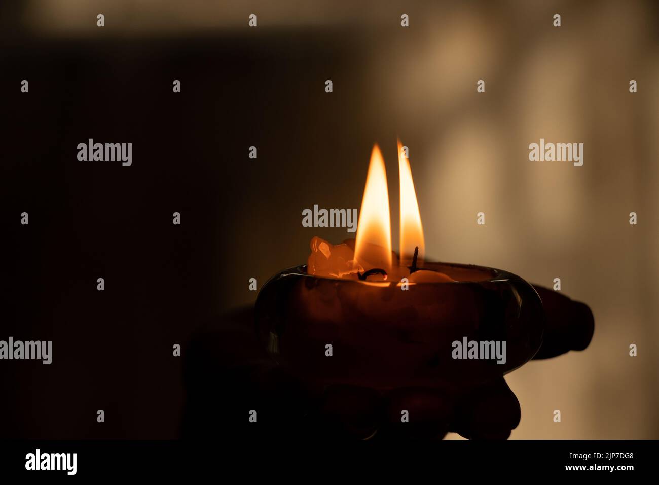 A woman's hand holds a burning candle in the dark, candle flame and ...