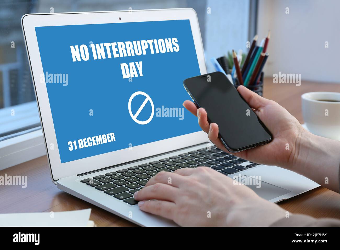Woman with mobile phone sitting near laptop with text NO INTERRUPTIONS ...