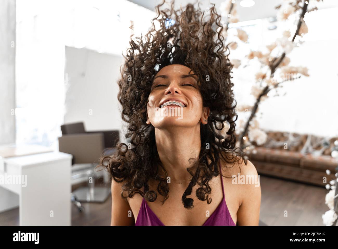 Photo with motion of a smiley woman with curly hair waving the hair in ...