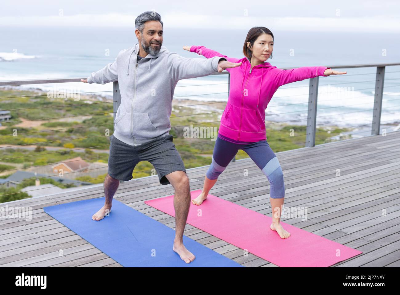 Happy diverse couple doing yoga together, stretching on balcony Stock ...
