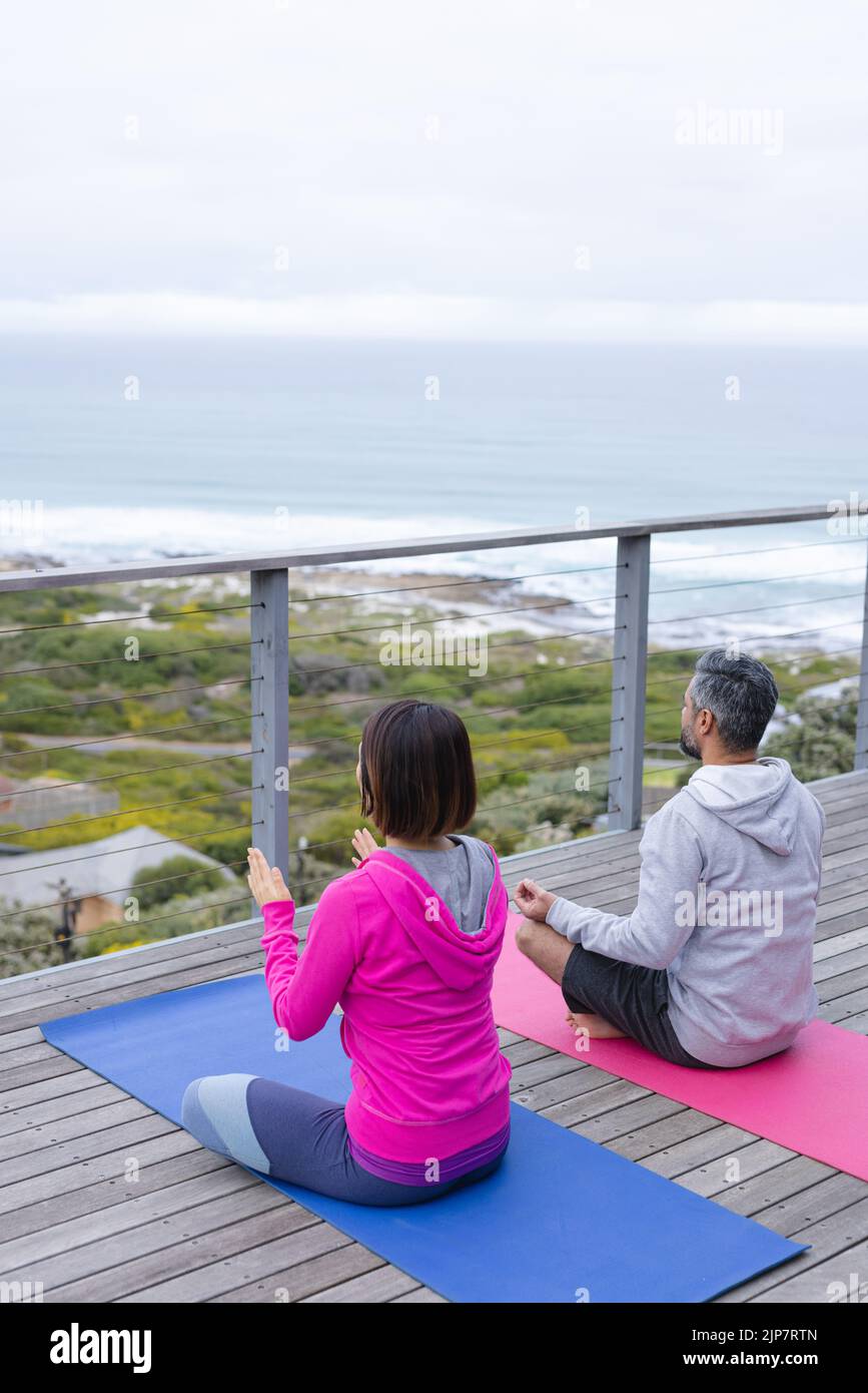 Happy diverse couple doing yoga together, meditating on balcony Stock ...