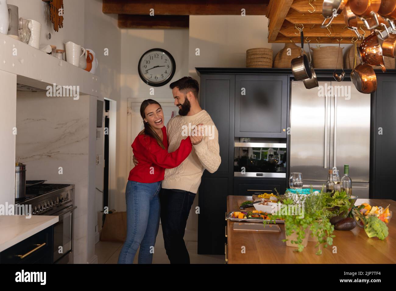 Happy caucasian couple having fun preparing food, smiling and dancing ...