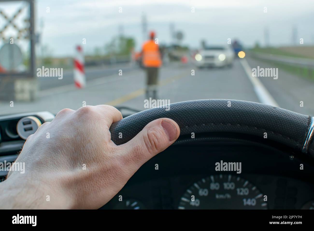 driver hand is on the steering wheel, which stands and passes oncoming ...