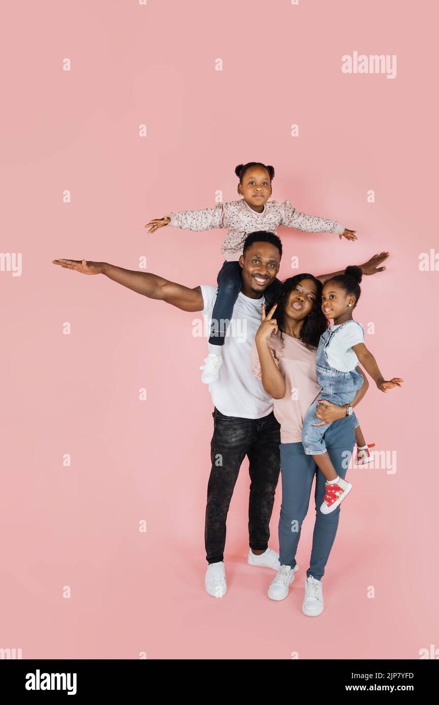 Family bonding concept. Joyful black man and woman holding daughters on ...