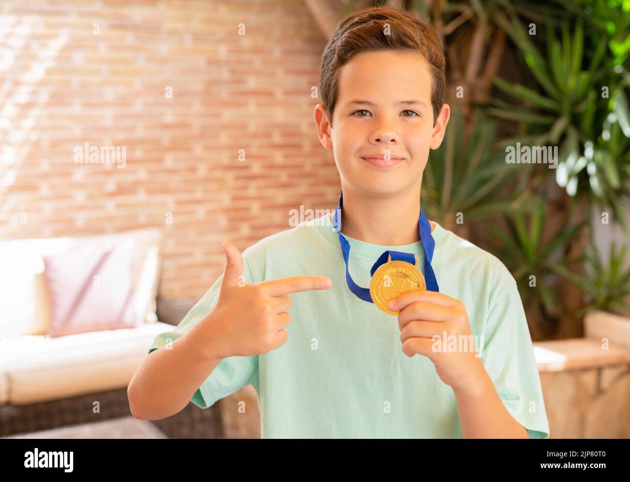 Cute child boy showing his gold medal standing on the terrace at home ...