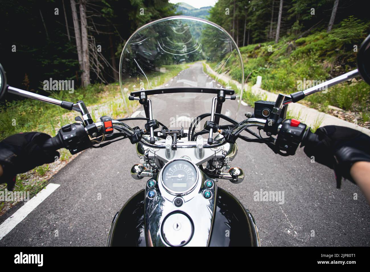 Close-up on the hands of a motorcycle driver riding on forest road ...