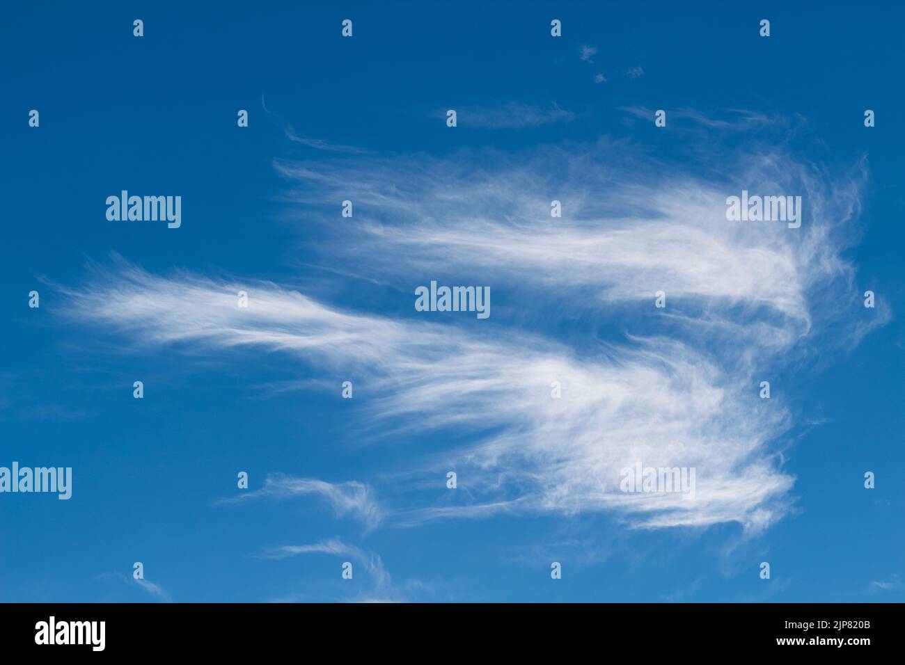 Beautiful thin cirrus clouds. White spindrift clouds in a shape of an angel on blue sky ...