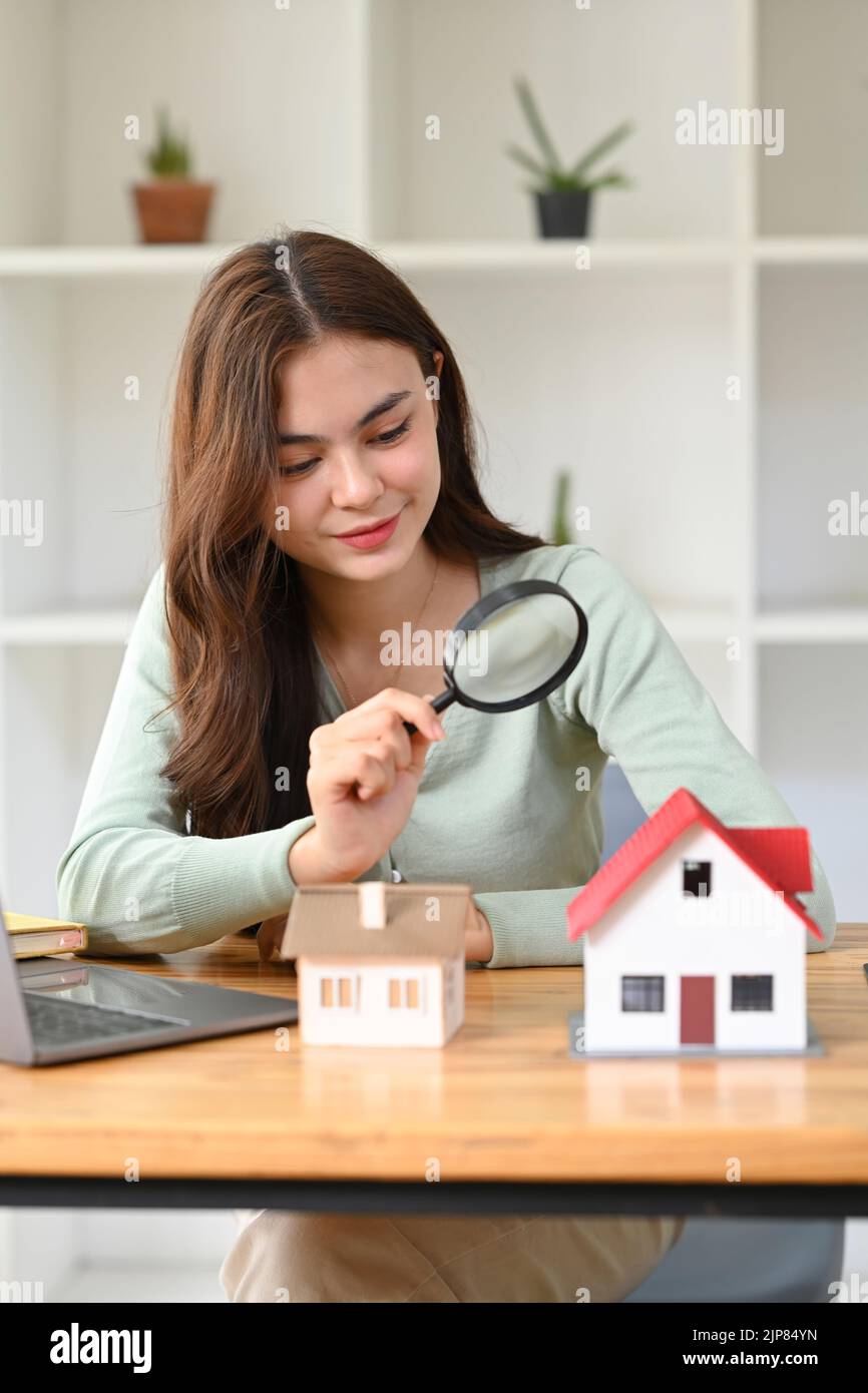 Female appraiser looking at house model through magnifying glass. Real ...