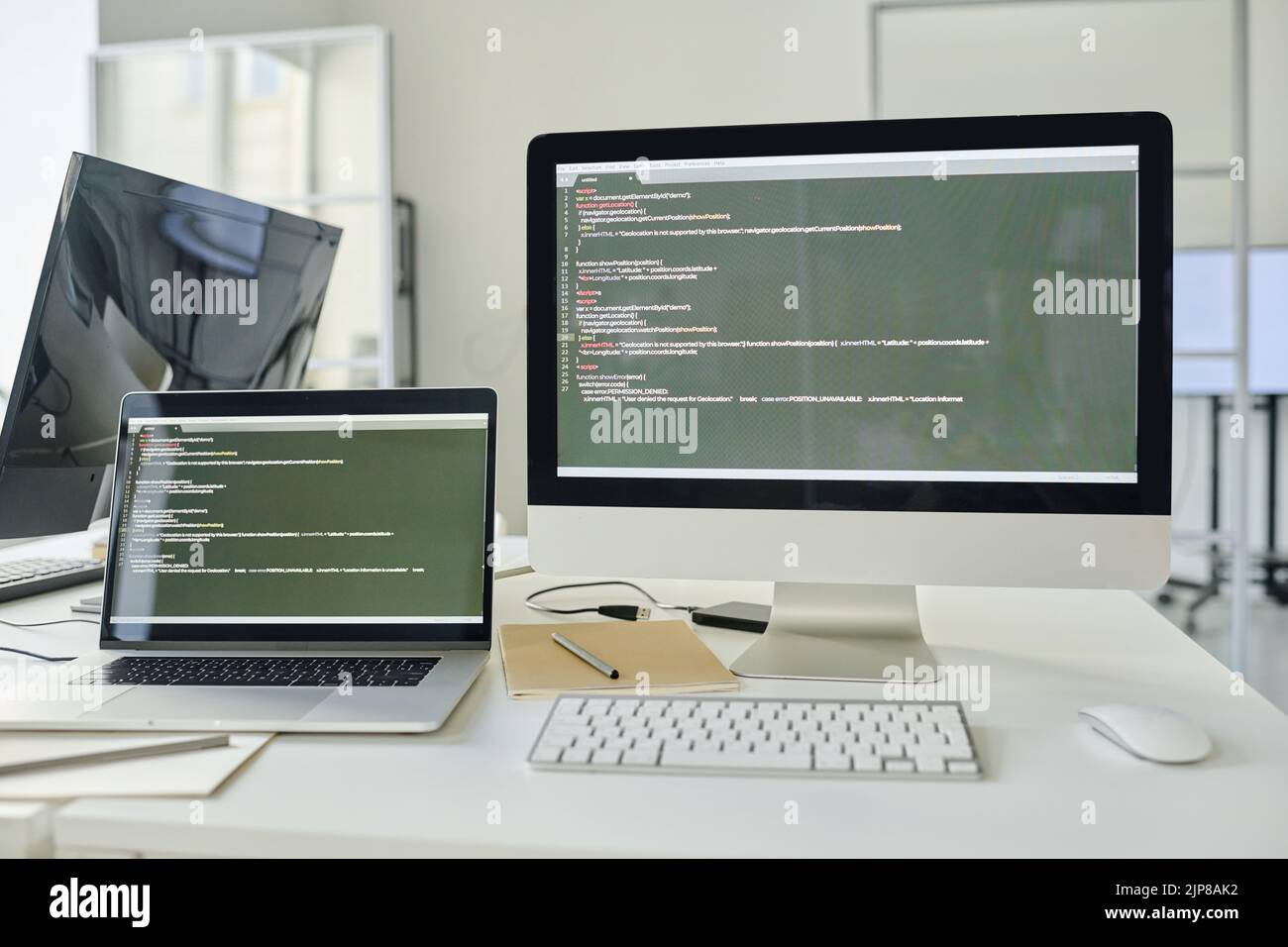 Horizontal image of workplace of programmer with computer and laptop with software on the screen ...