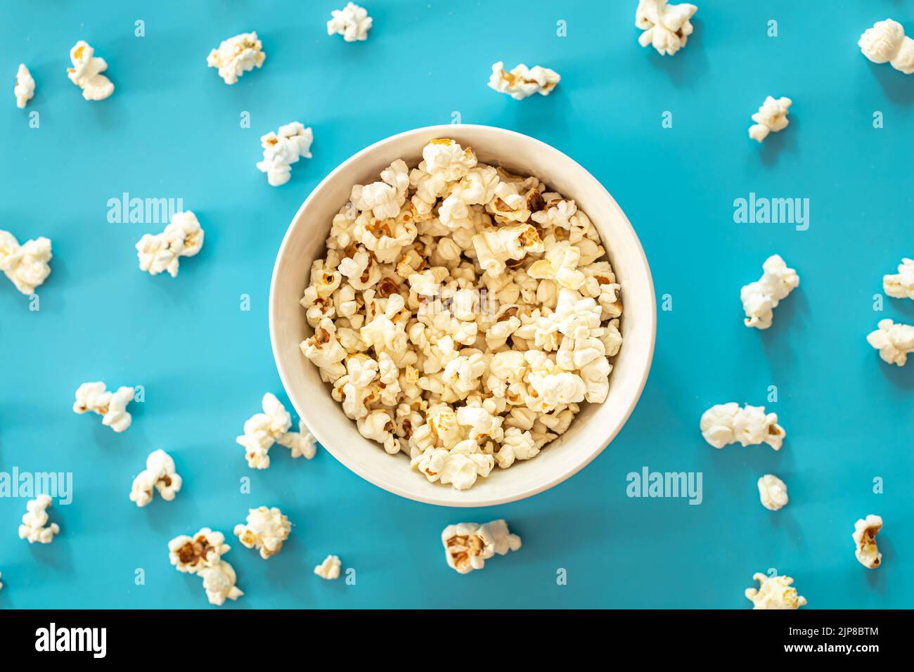 Plate with popcorn on a blue background, flat lay Stock Photo - Alamy