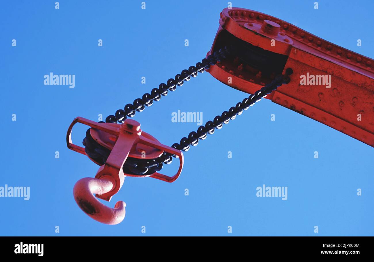 A low angle shot of the red chain winch hanging from the crane with ...