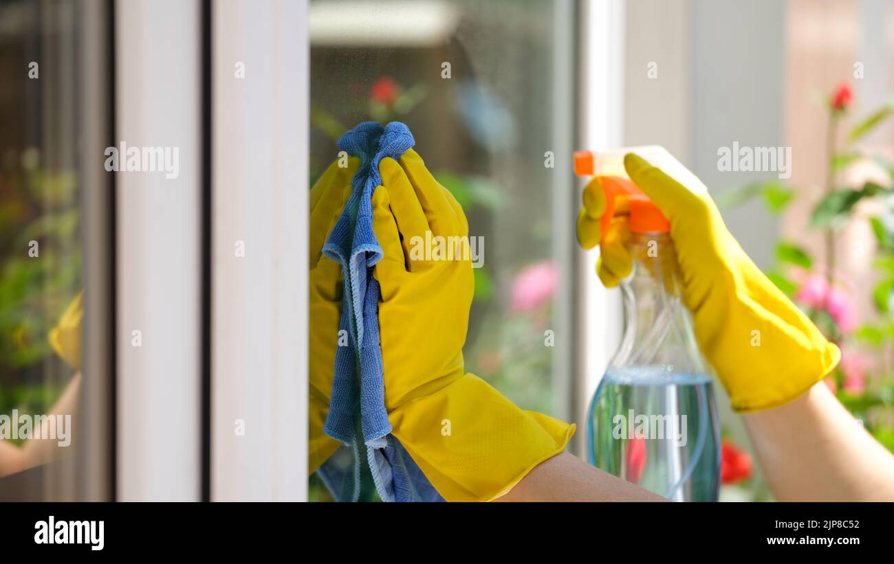 Woman applying detergent spray and rag for cleaning window outside ...