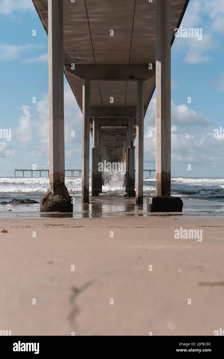 A low-angle shot of the base of an old bridge in the sea with a ...