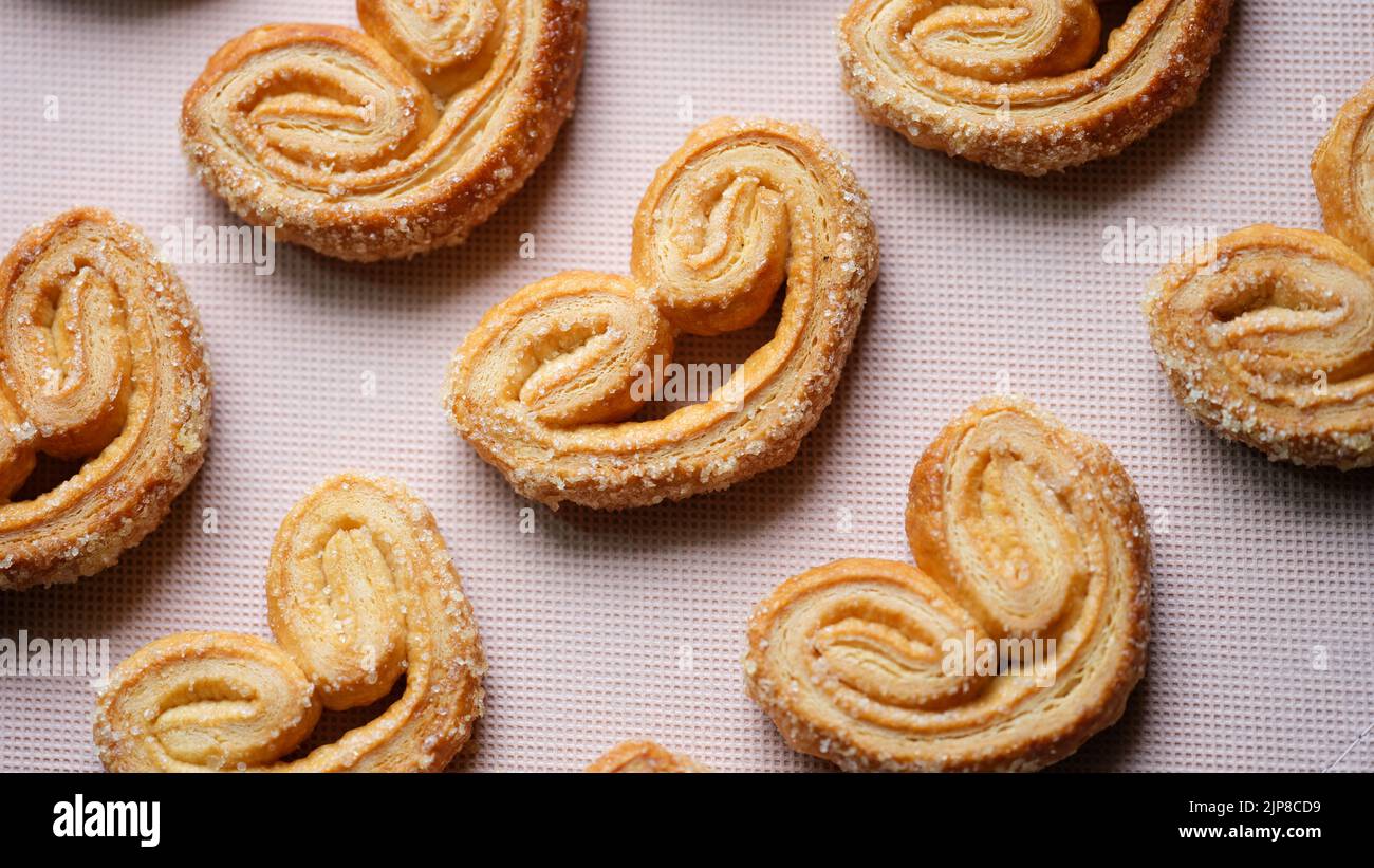 Tasty puff pastry cookies with sugar sprinkle on pink background Stock ...