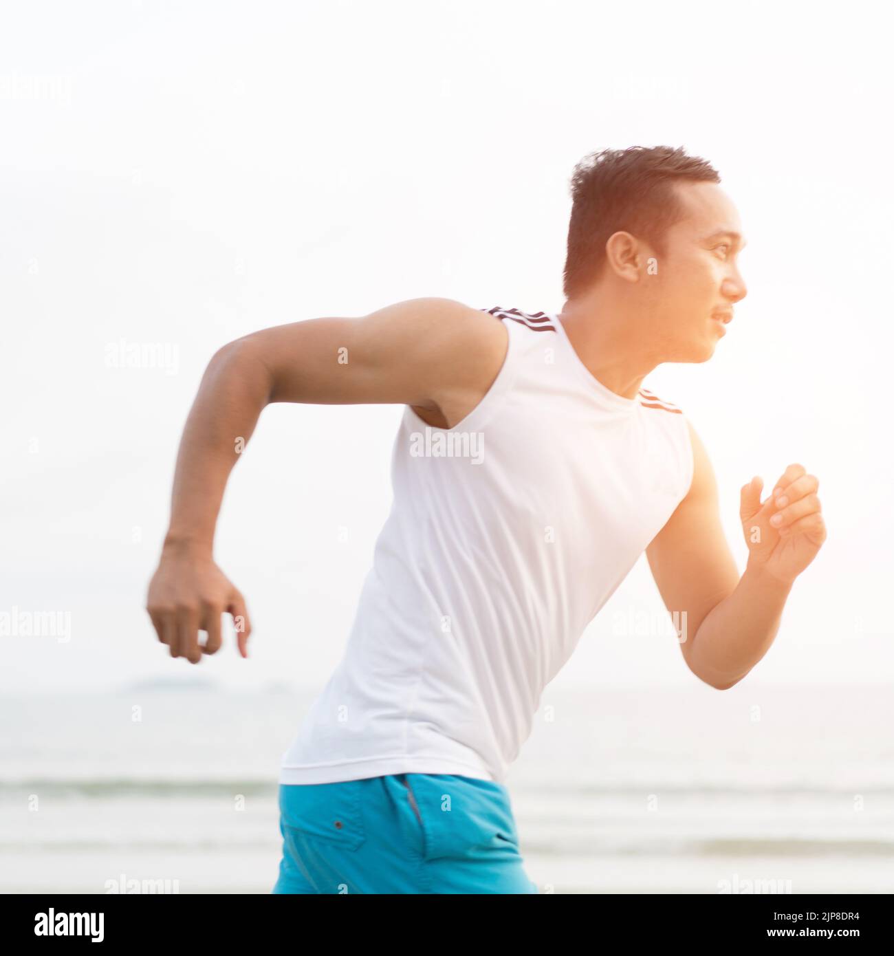 asian sport man running along seaside. running on beach with healthy ...