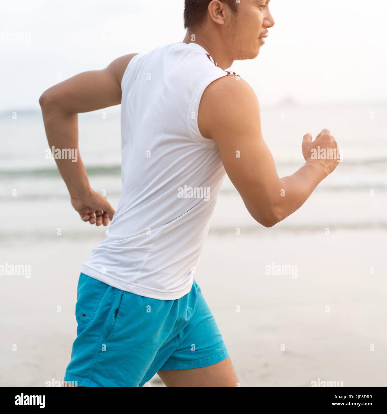 asian sport man running along seaside. running on beach with healthy ...