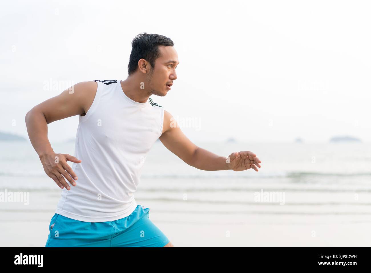 asian sport man running along seaside. running on beach with healthy ...