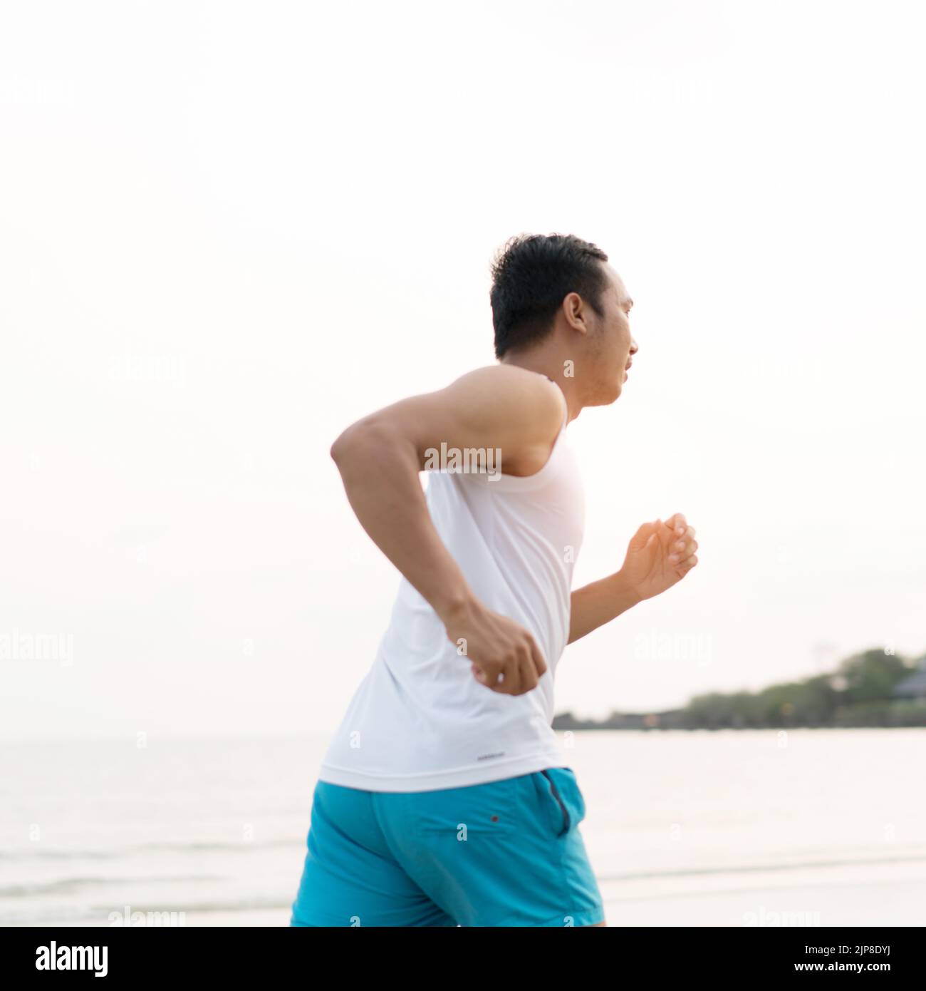 asian sport man running along seaside. running on beach with healthy ...