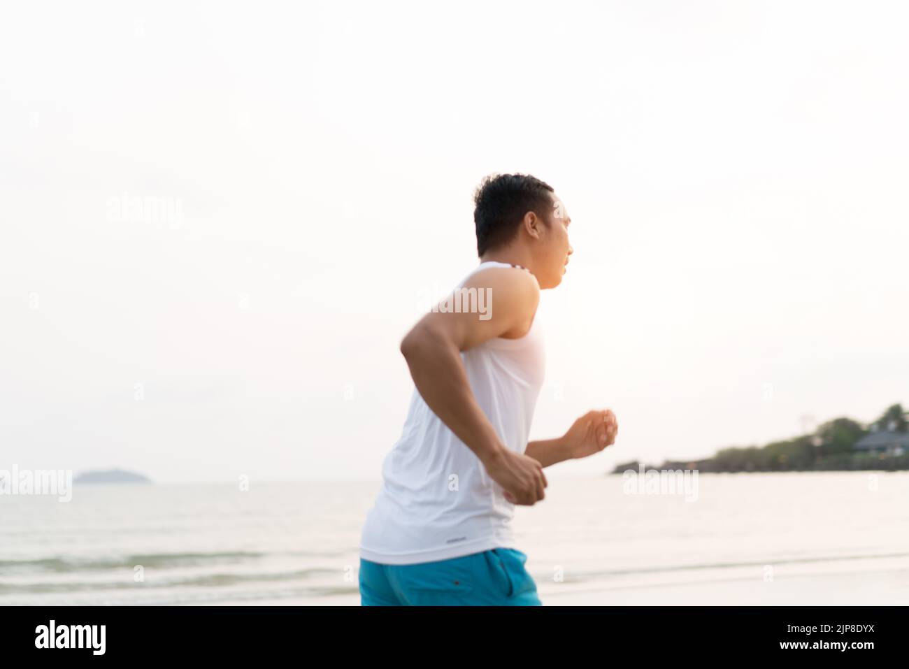 asian sport man running along seaside. running on beach with healthy ...