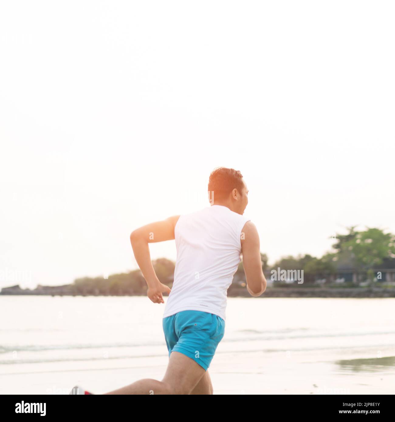 asian sport man running along seaside. running on beach with healthy ...