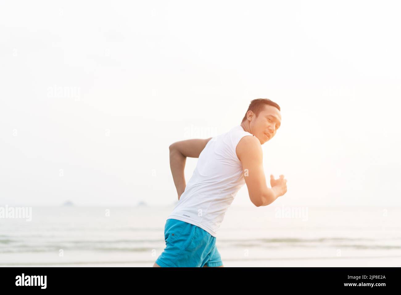 asian sport man running along seaside. running on beach with healthy ...