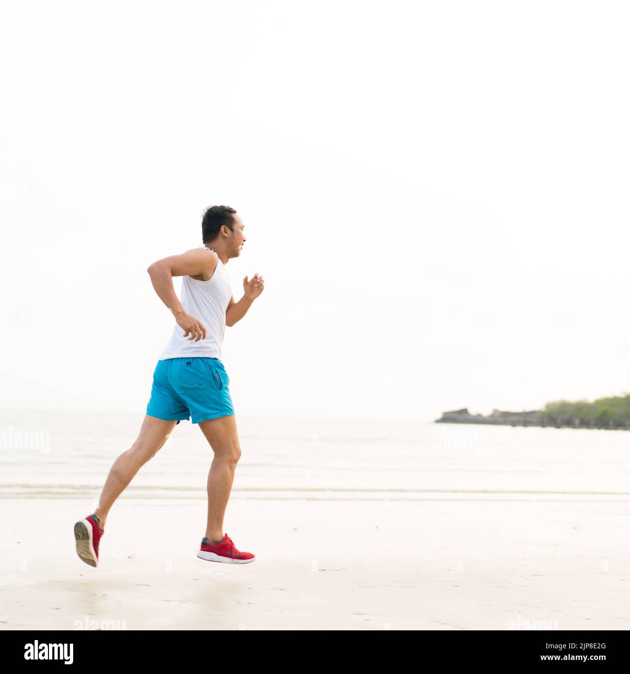 asian sport man running along seaside. running on beach with healthy ...