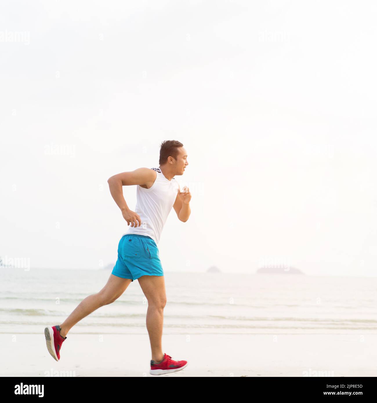 asian sport man running along seaside. running on beach with healthy ...