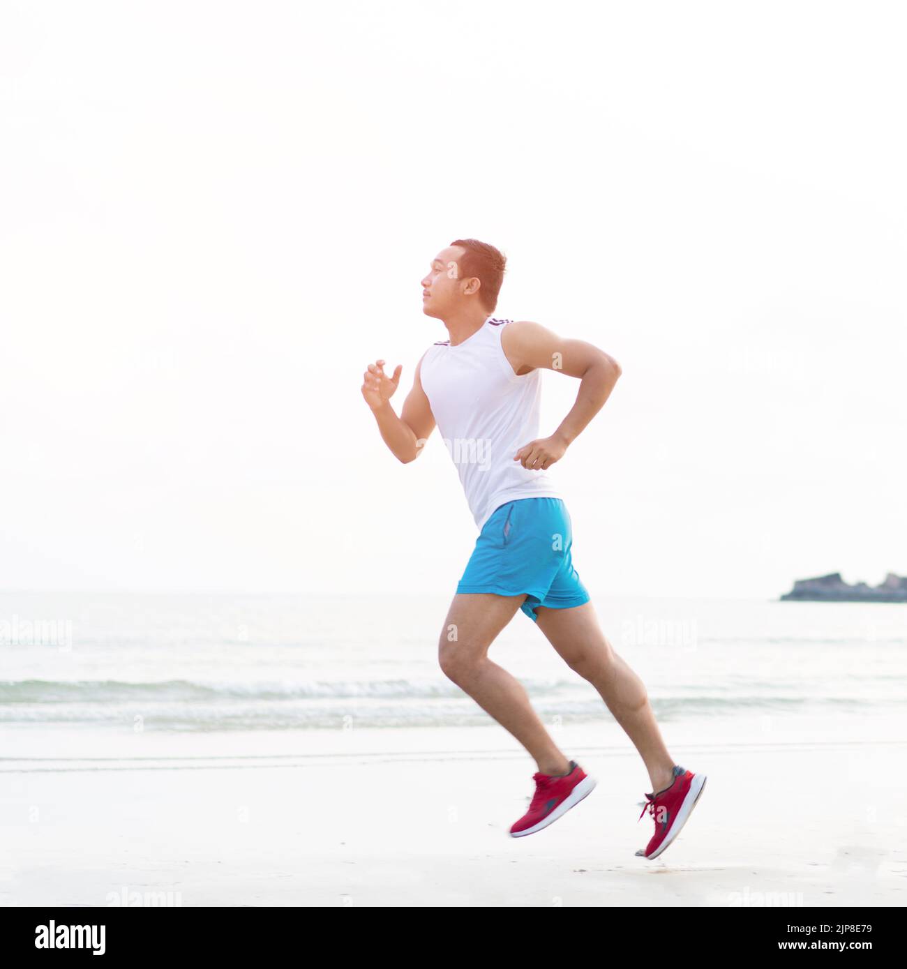 asian sport man running along seaside. running on beach with healthy ...