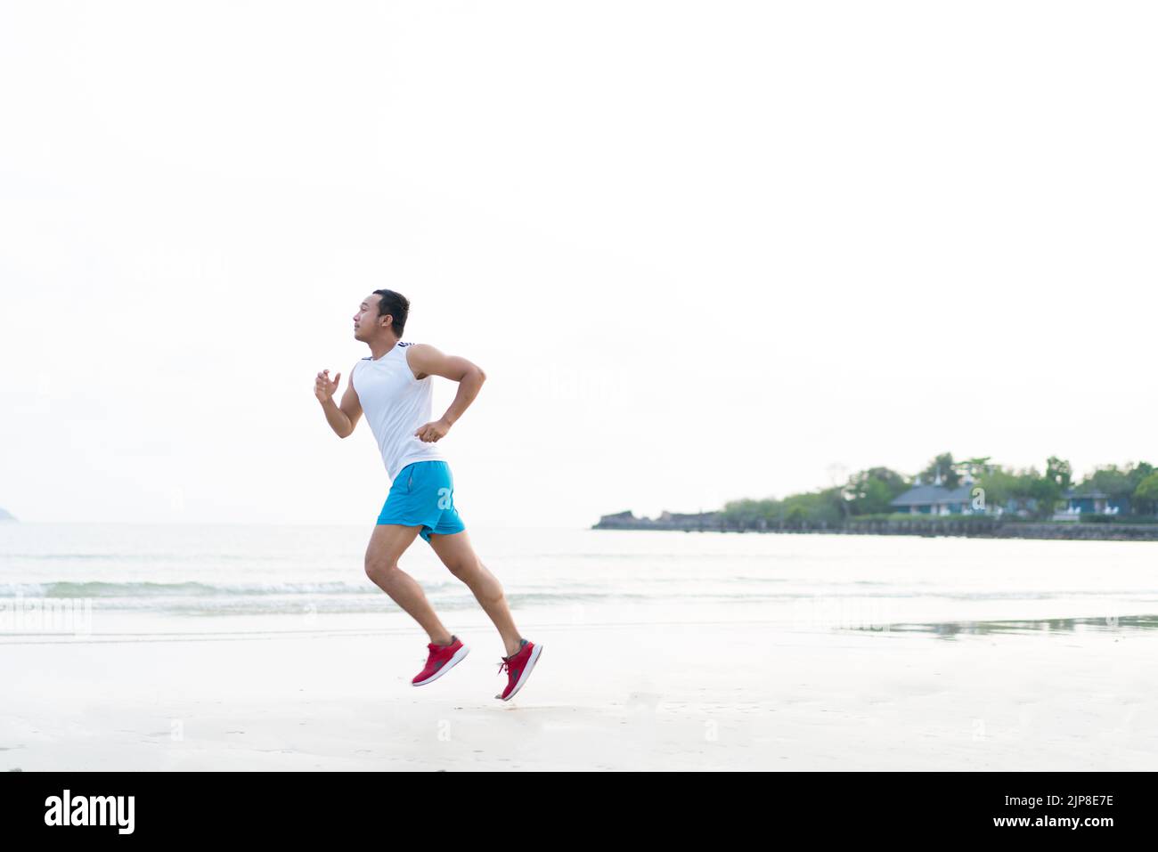 asian sport man running along seaside. running on beach with healthy ...