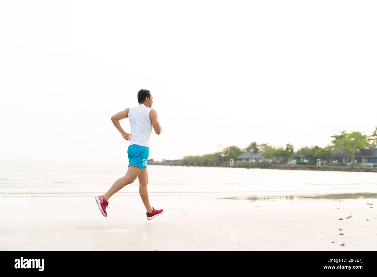 asian sport man running along seaside. running on beach with healthy ...