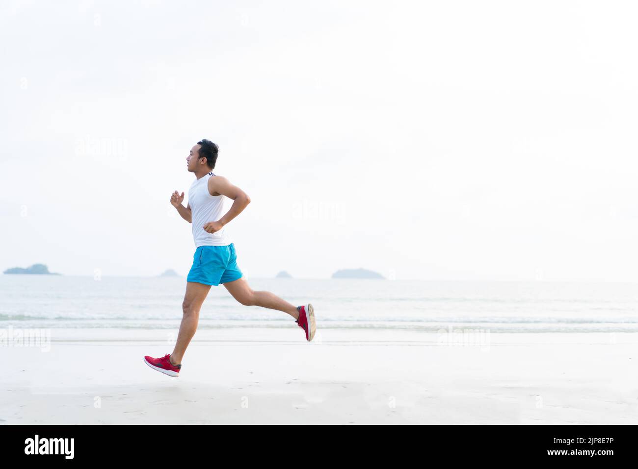 asian sport man running along seaside. running on beach with healthy ...