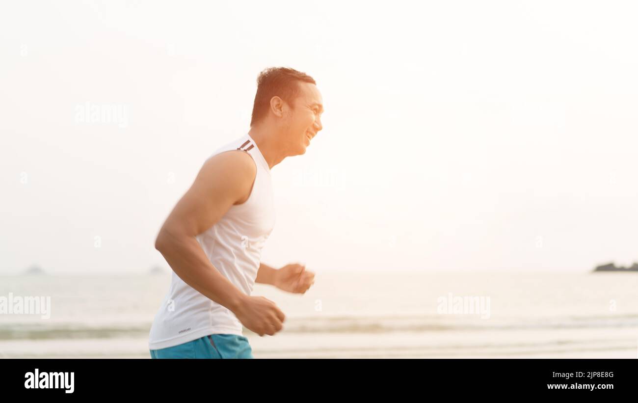 asian sport man running along seaside. running on beach with healthy ...