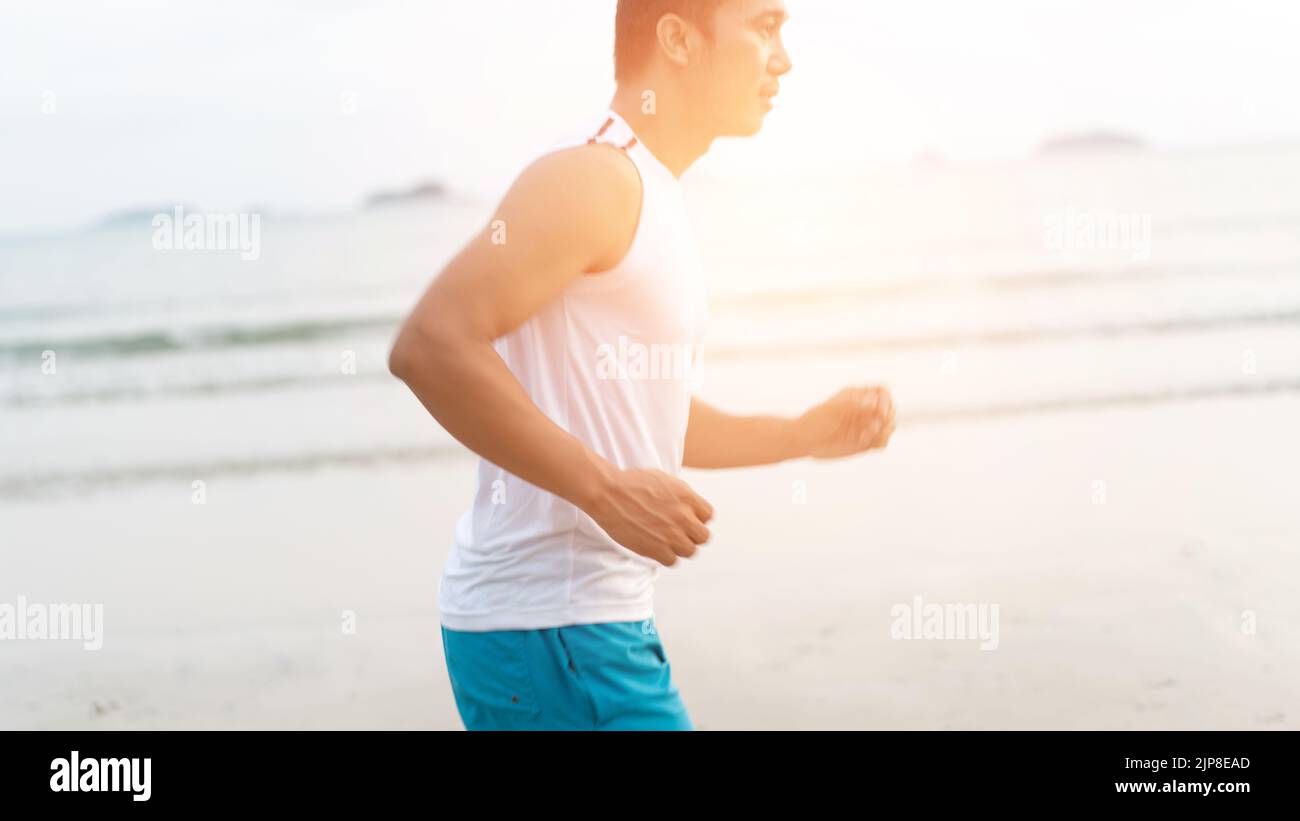 asian sport man running along seaside. running on beach with healthy ...